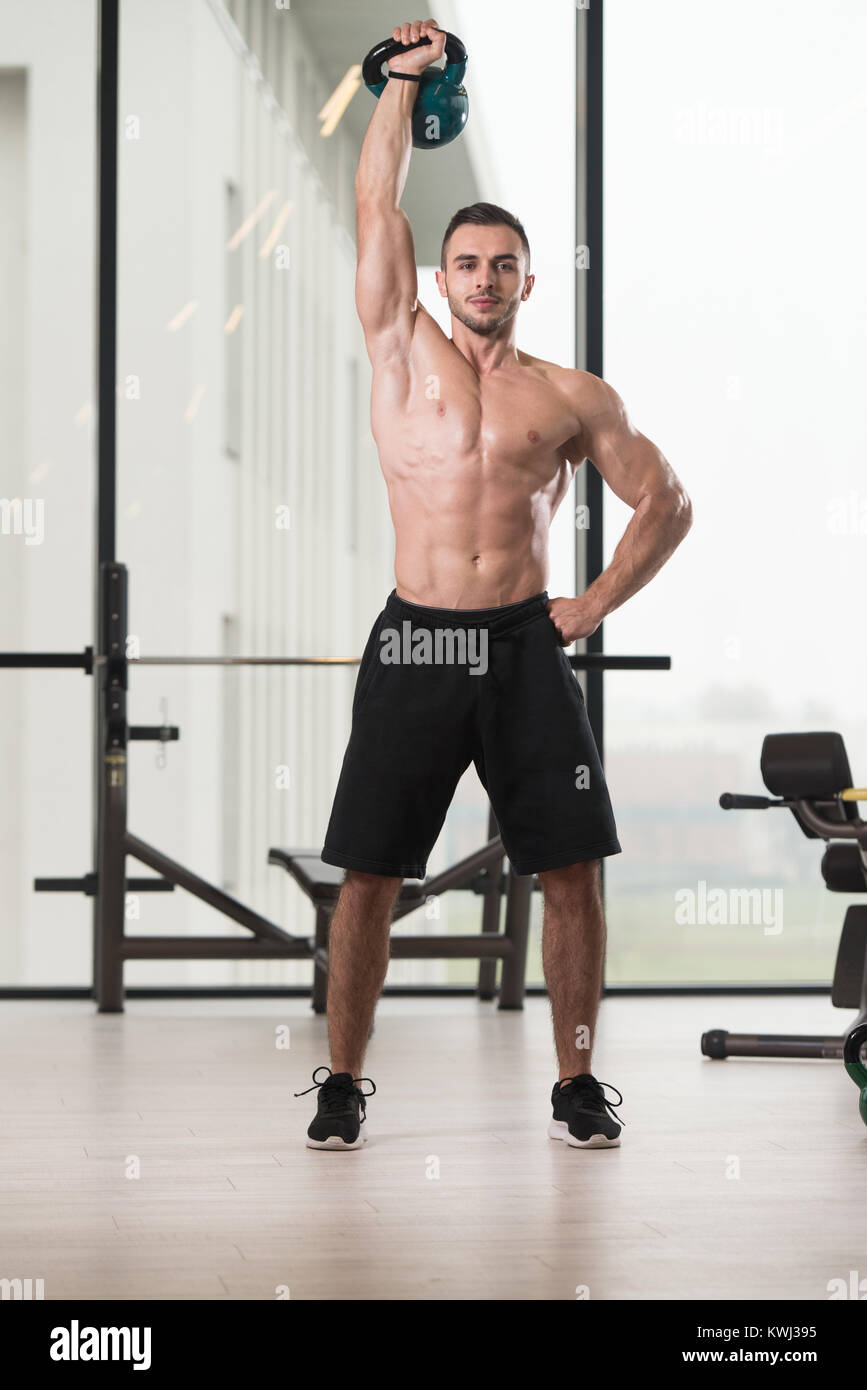 Man Working Out With Kettle Bell In A Dark Gym - Bodybuilder Doing ...