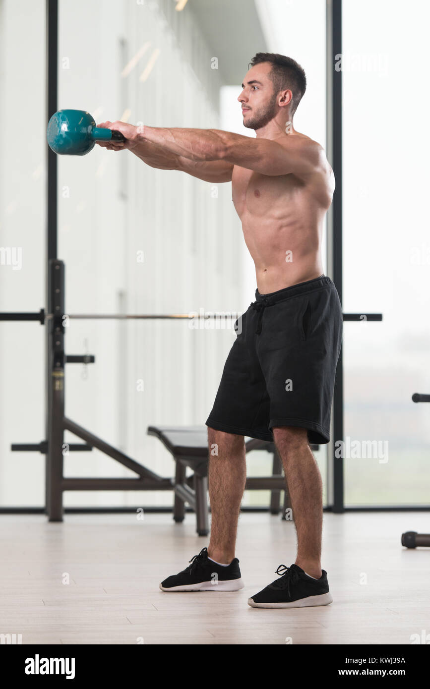 Man Working Out With Kettle Bell In A Dark Gym - Bodybuilder Doing ...