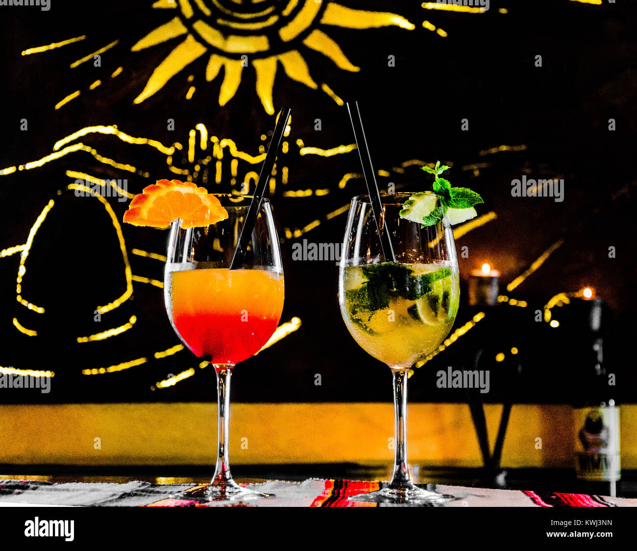 Glass of Tequila Sunrise and Mojito kept side by side in dim light, pub ...