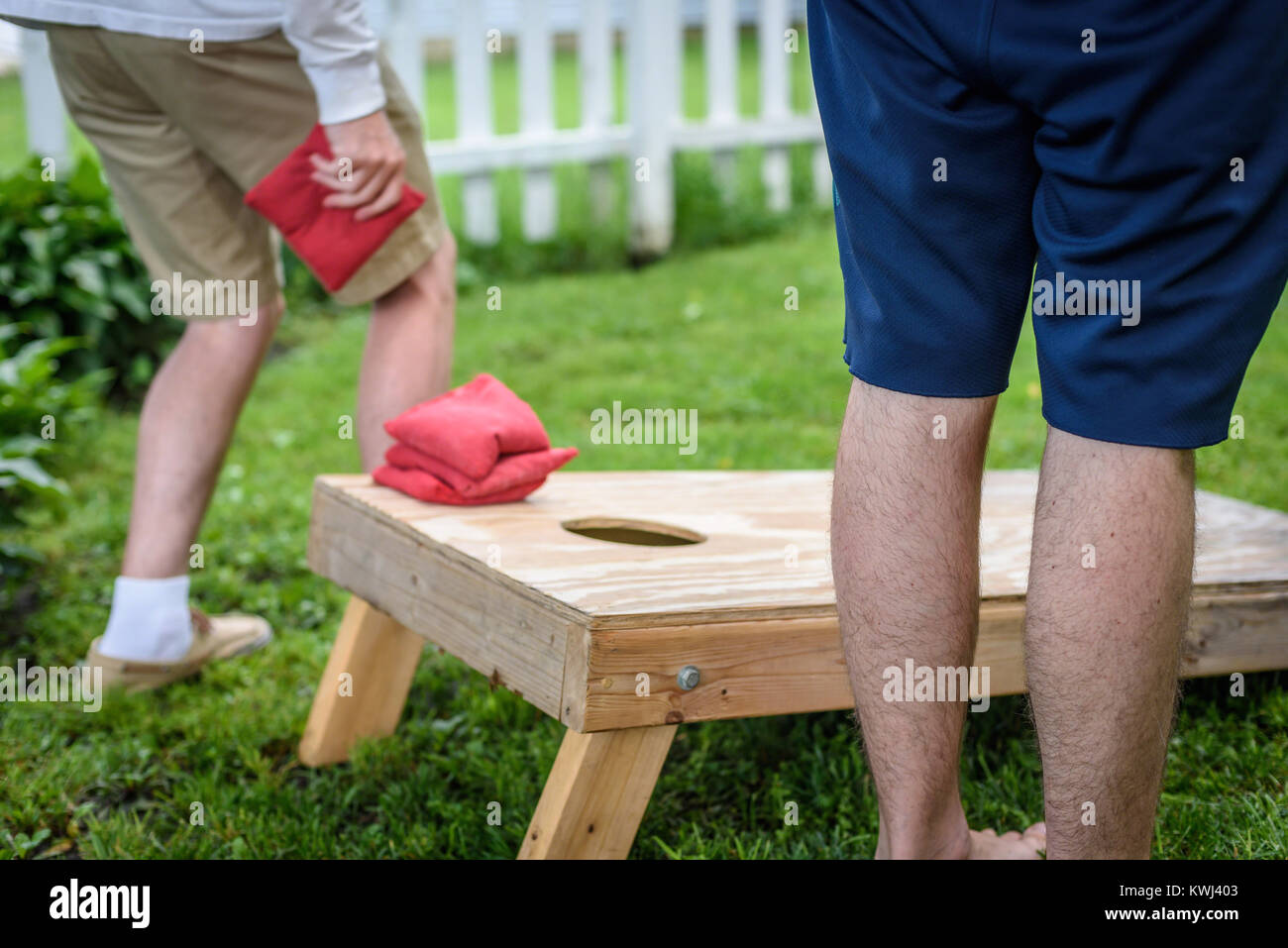 blurred action of two guys playing cornhole game in backyard Stock ...