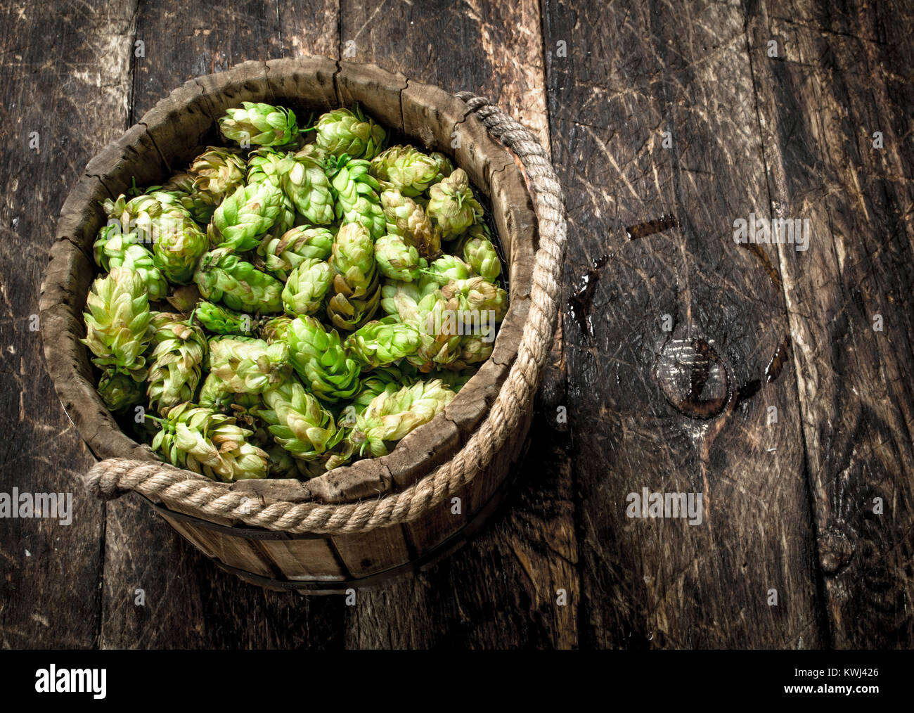 Green hops for beer in a wooden bucket. On a wooden background Stock ...