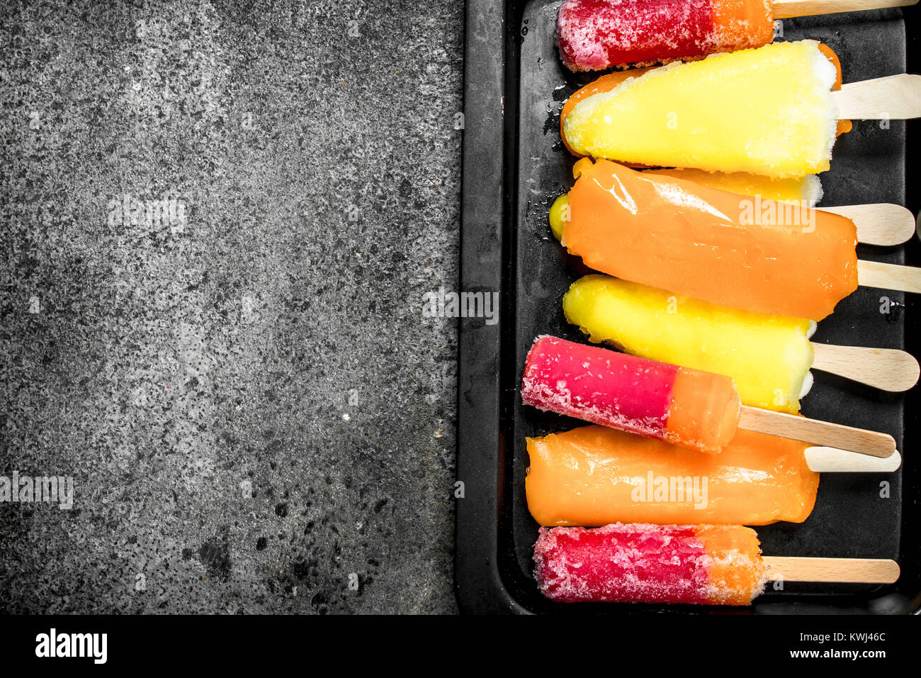 Multicolored fruit ice made from fruits. On a rustic background Stock ...