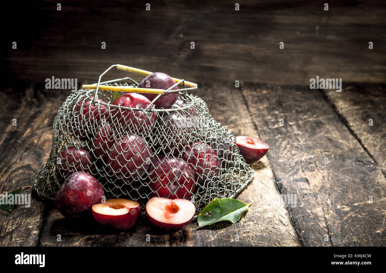 Fresh plums in a mesh bag. On a wooden background Stock Photo - Alamy