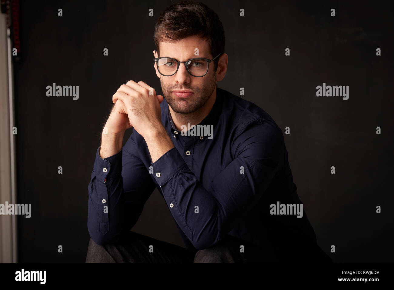 Shot of a thinking young man sitting at dark background Stock Photo - Alamy