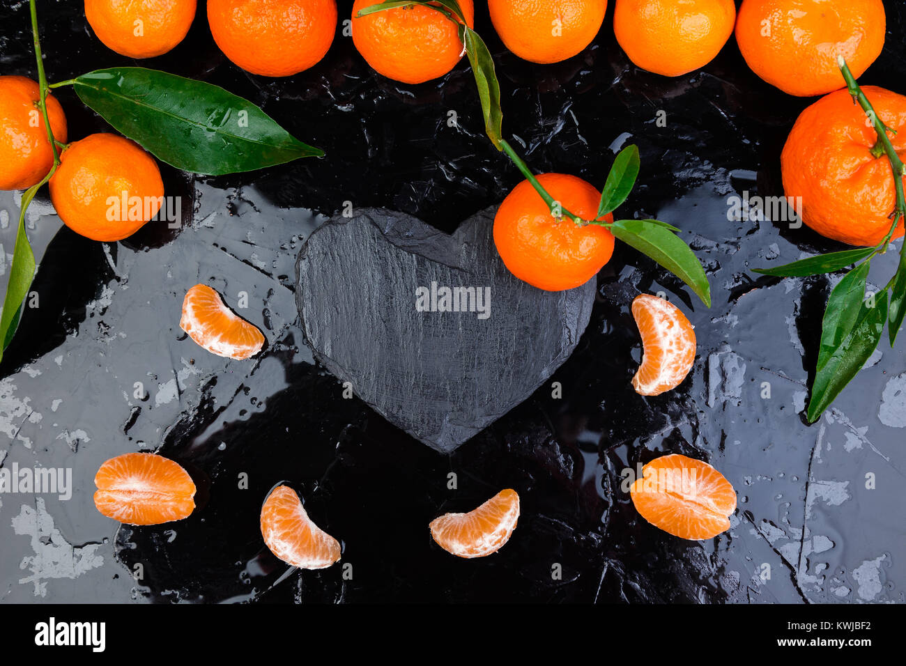 Tangerine around with black slate heart shaped. Frame. Copy space ...