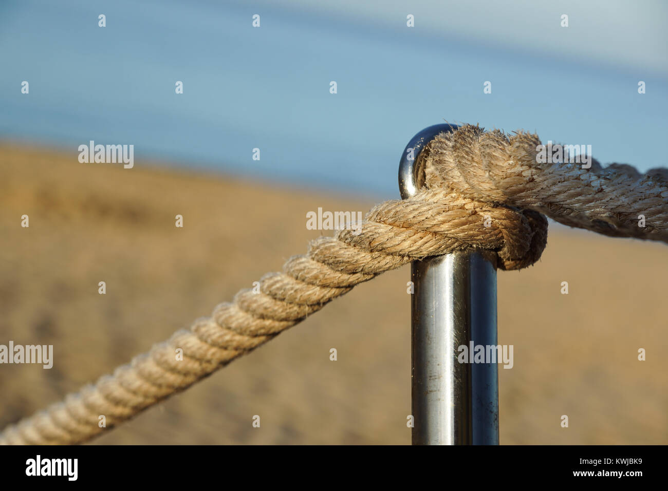 Detail of rope railing of beach walkway, old metal pole, seaside ...