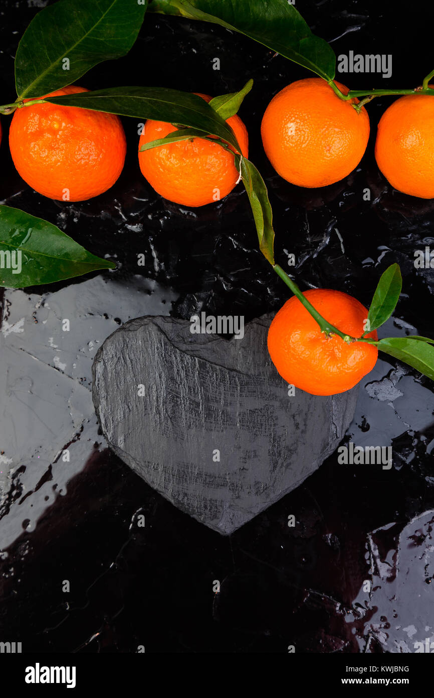 Tangerine around with black slate heart shaped. Frame. Copy space ...