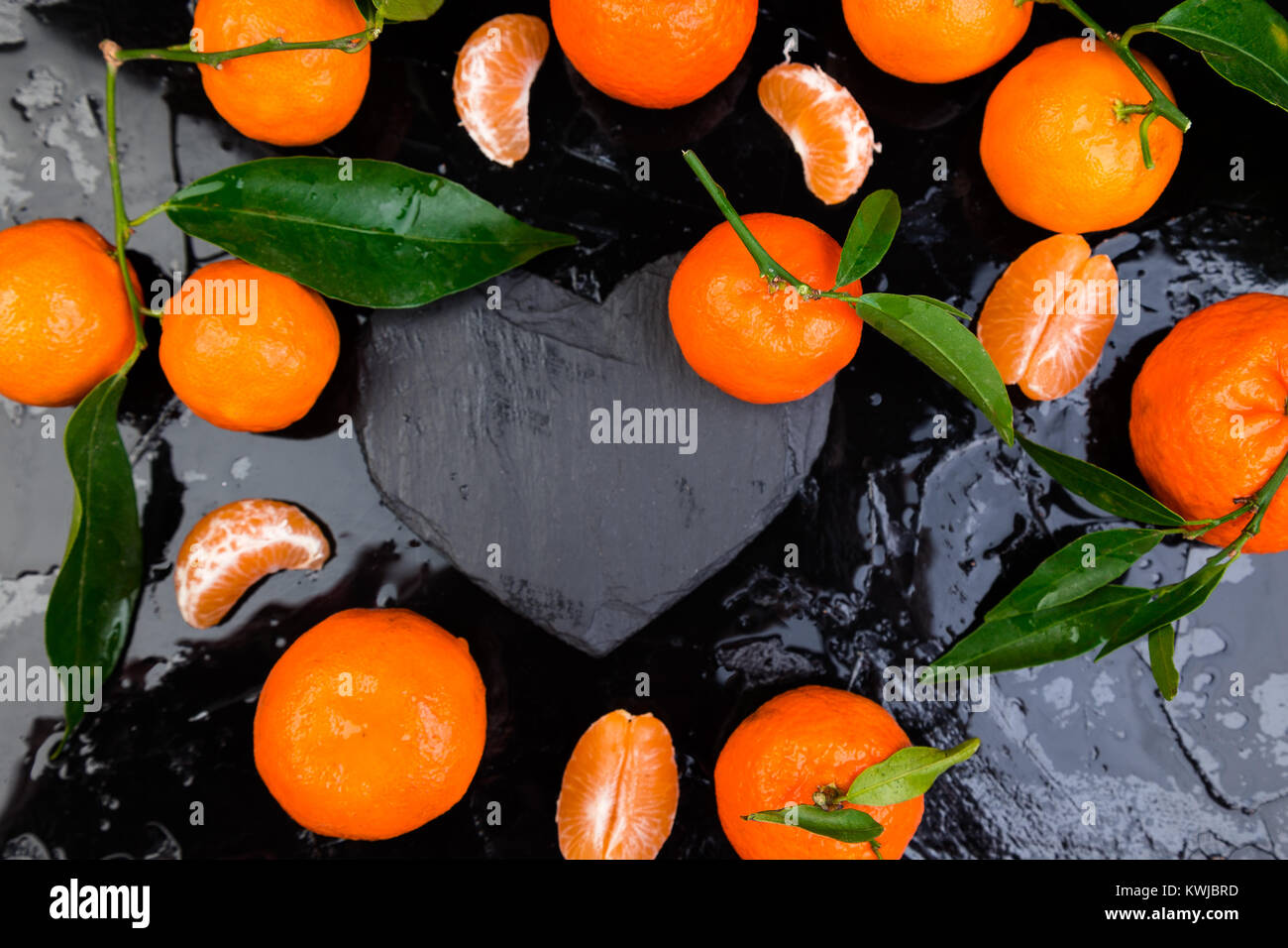 Tangerine around with black slate heart shaped. Frame. Copy space ...