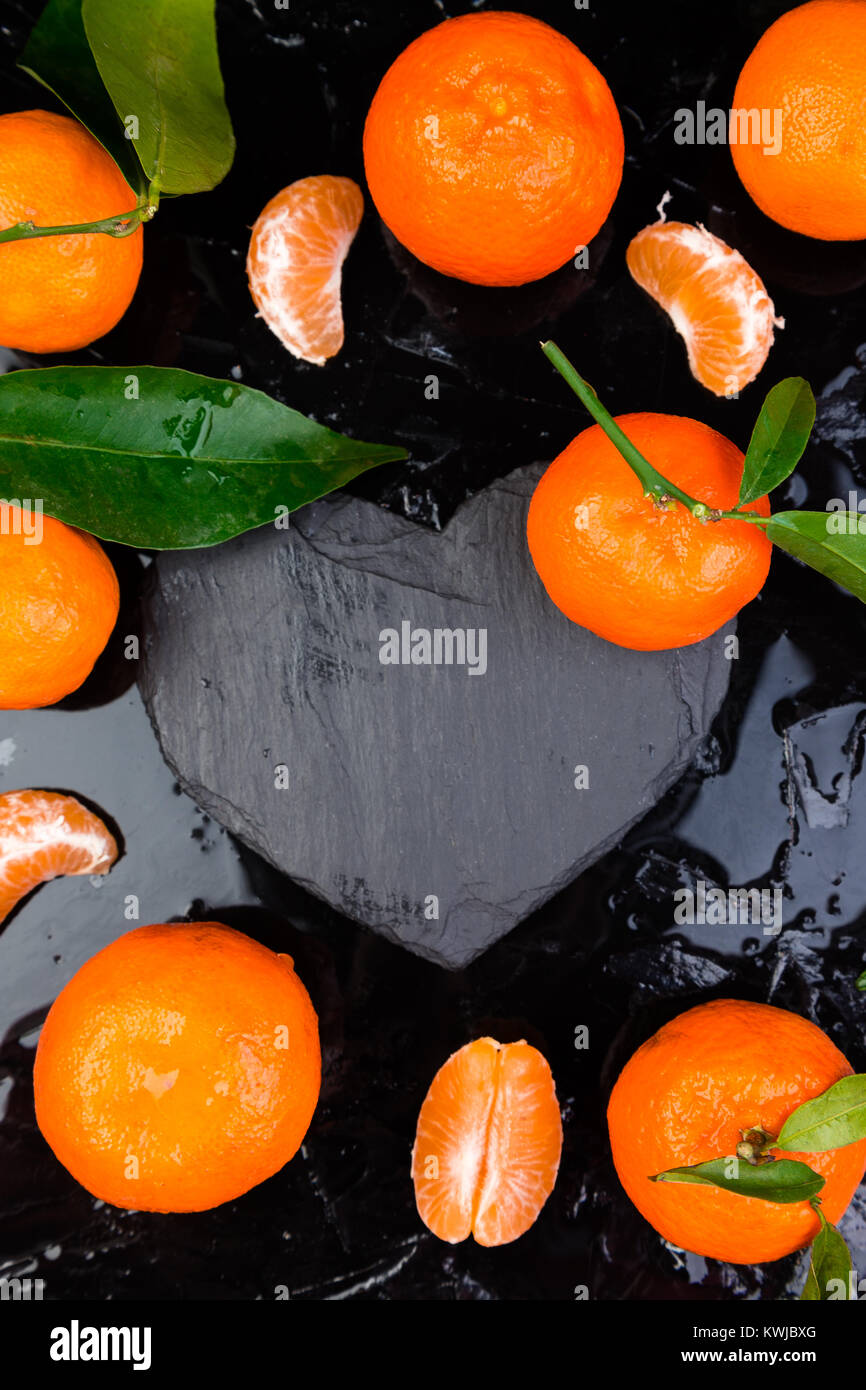 Tangerine around with black slate heart shaped. Frame. Copy space ...