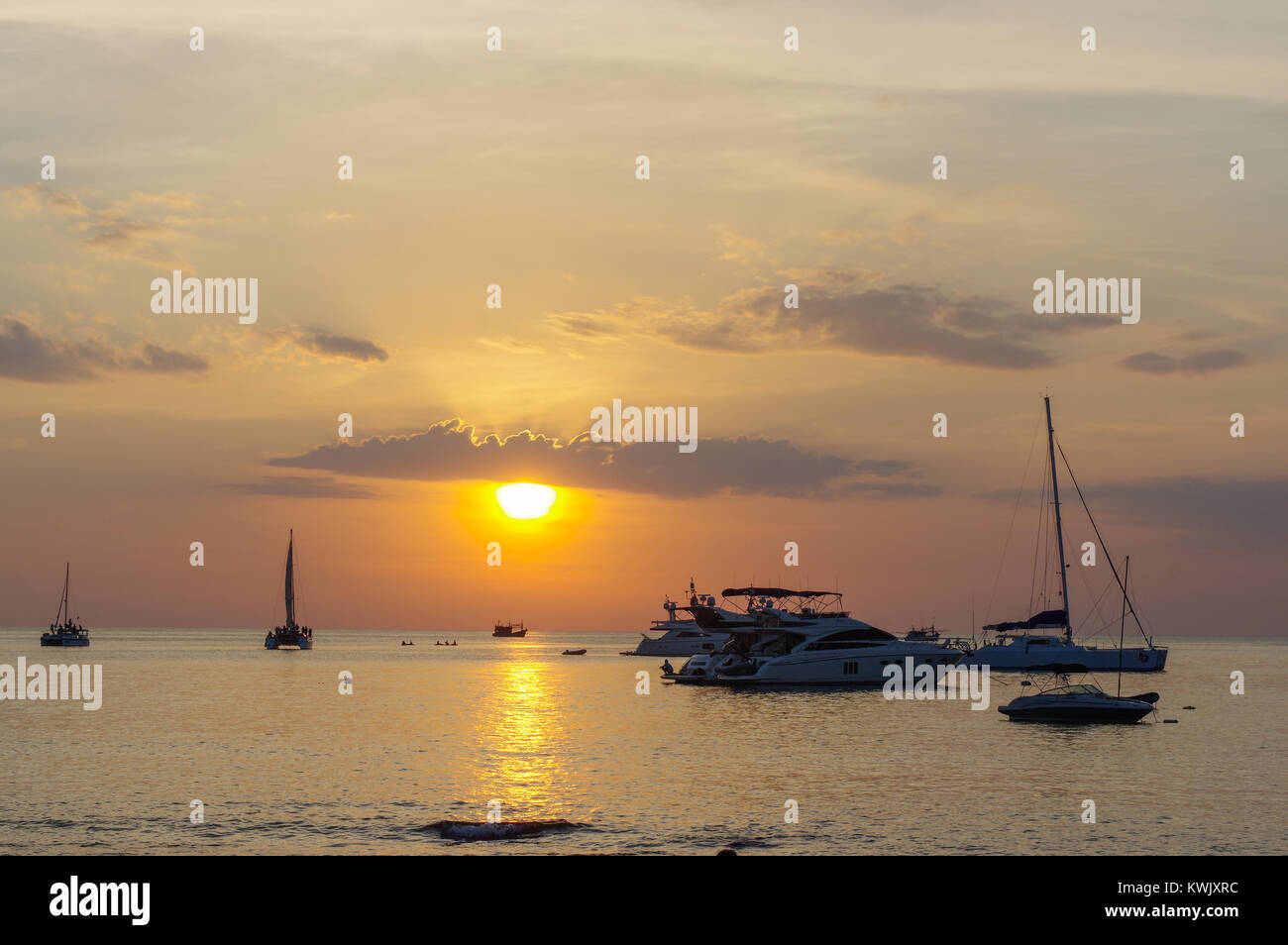 amazing tropical orange sunset over water, with rock silhouettes and a ...