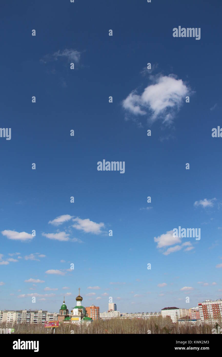 Blue clear day sky with white clouds and sunlight. A city landscape ...