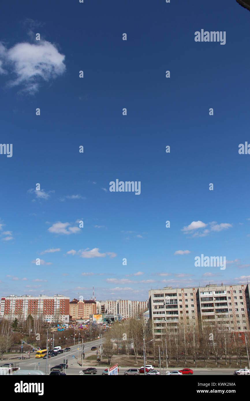 Blue clear day sky with white clouds and sunlight. A city landscape ...