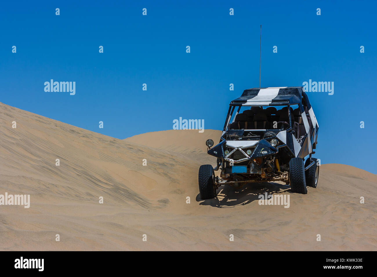 Dune buggy over a sand dune with blue sky in the desert, Huacachina ...