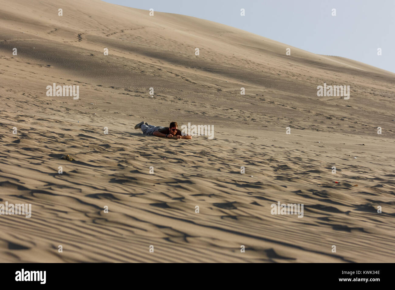 Picture of a young man sandboarding at sunset, Huacachina, Ica, Peru ...