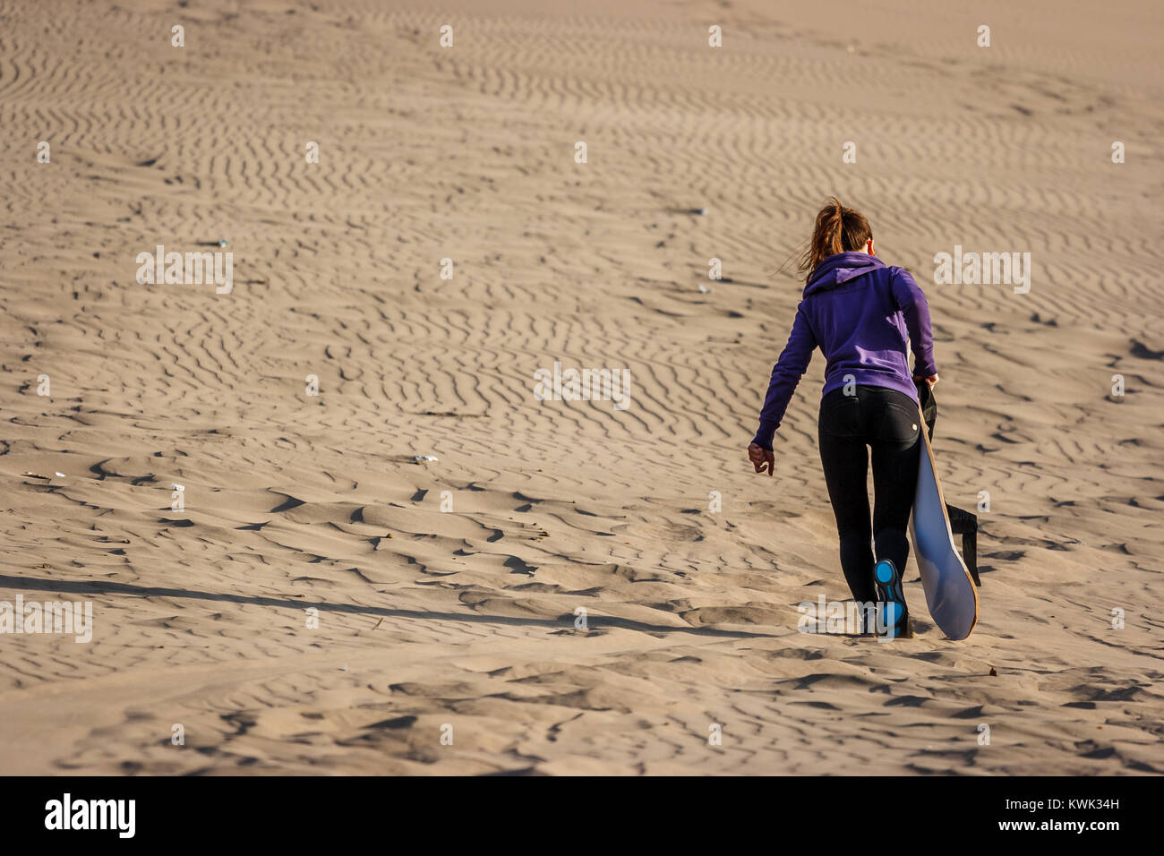 Picture of a young woman sandboarding at sunset, Huacachina, Ica, Peru ...