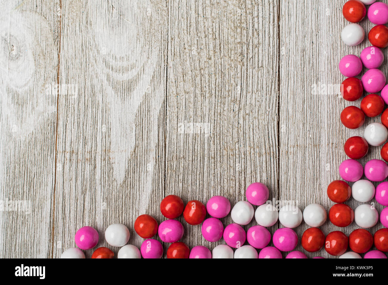 Round red, pink and white candies border the side and bottom of a white ...