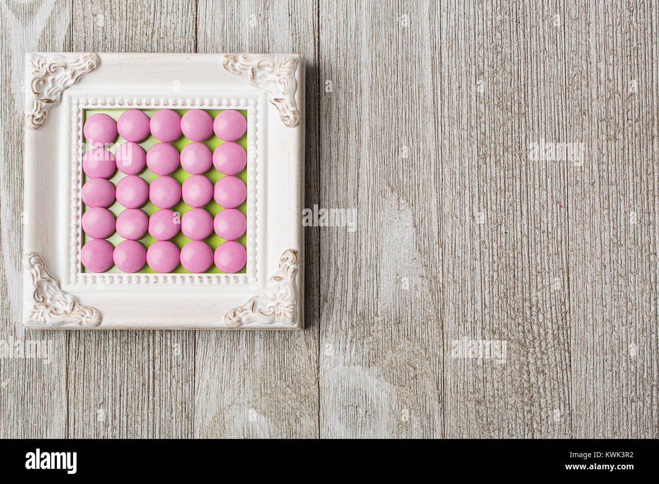 Vintage frame with pink round candy arranged in the center placed on a ...