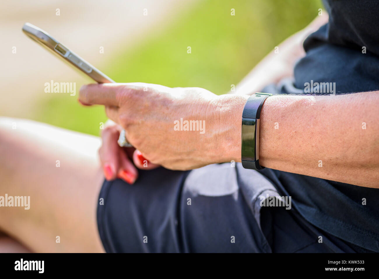 closeup of woman wearing smart watch sitting on bench checking smart ...