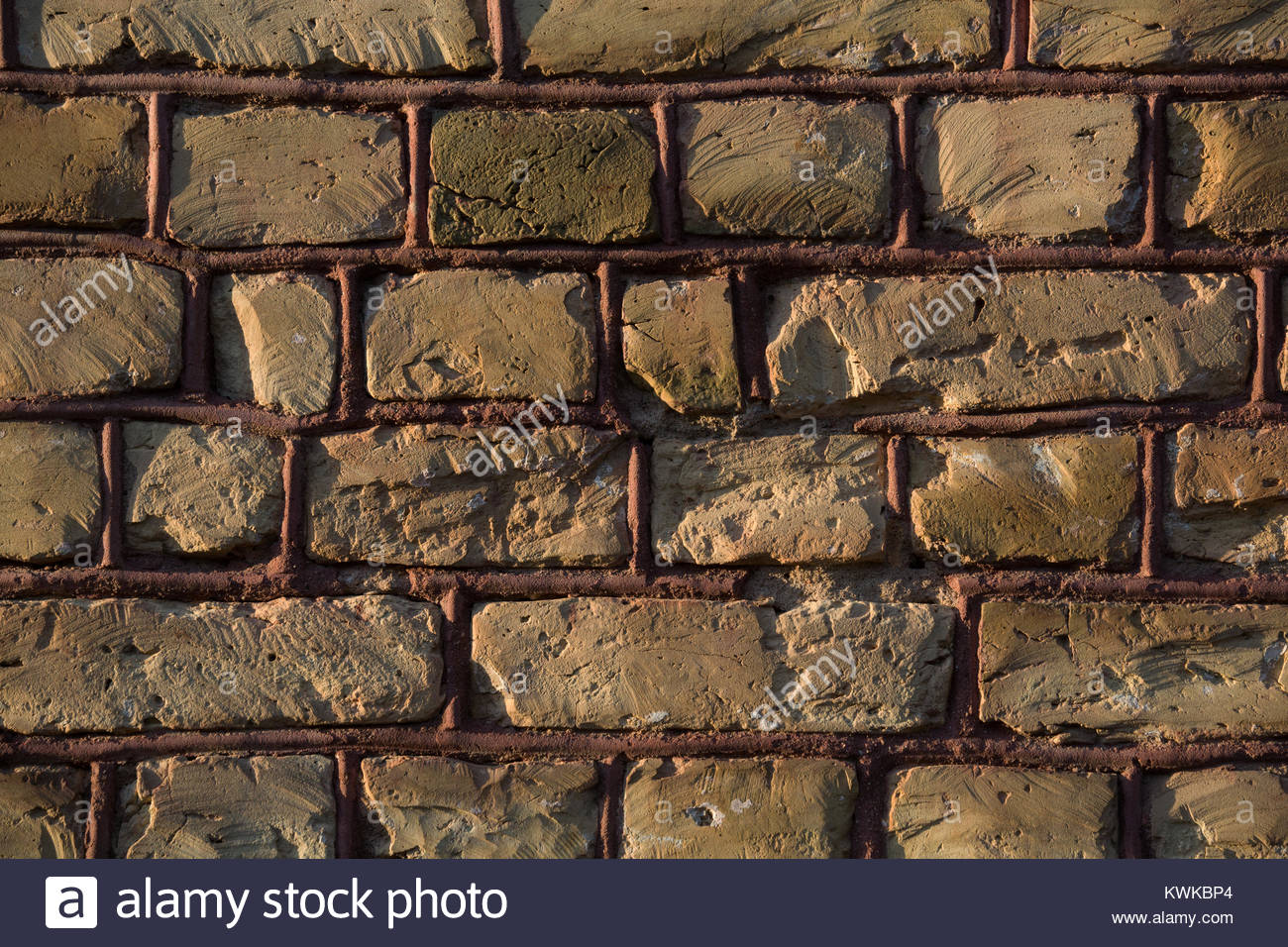 Evening sunlight on a brown brick wall in summertime highlights the ...