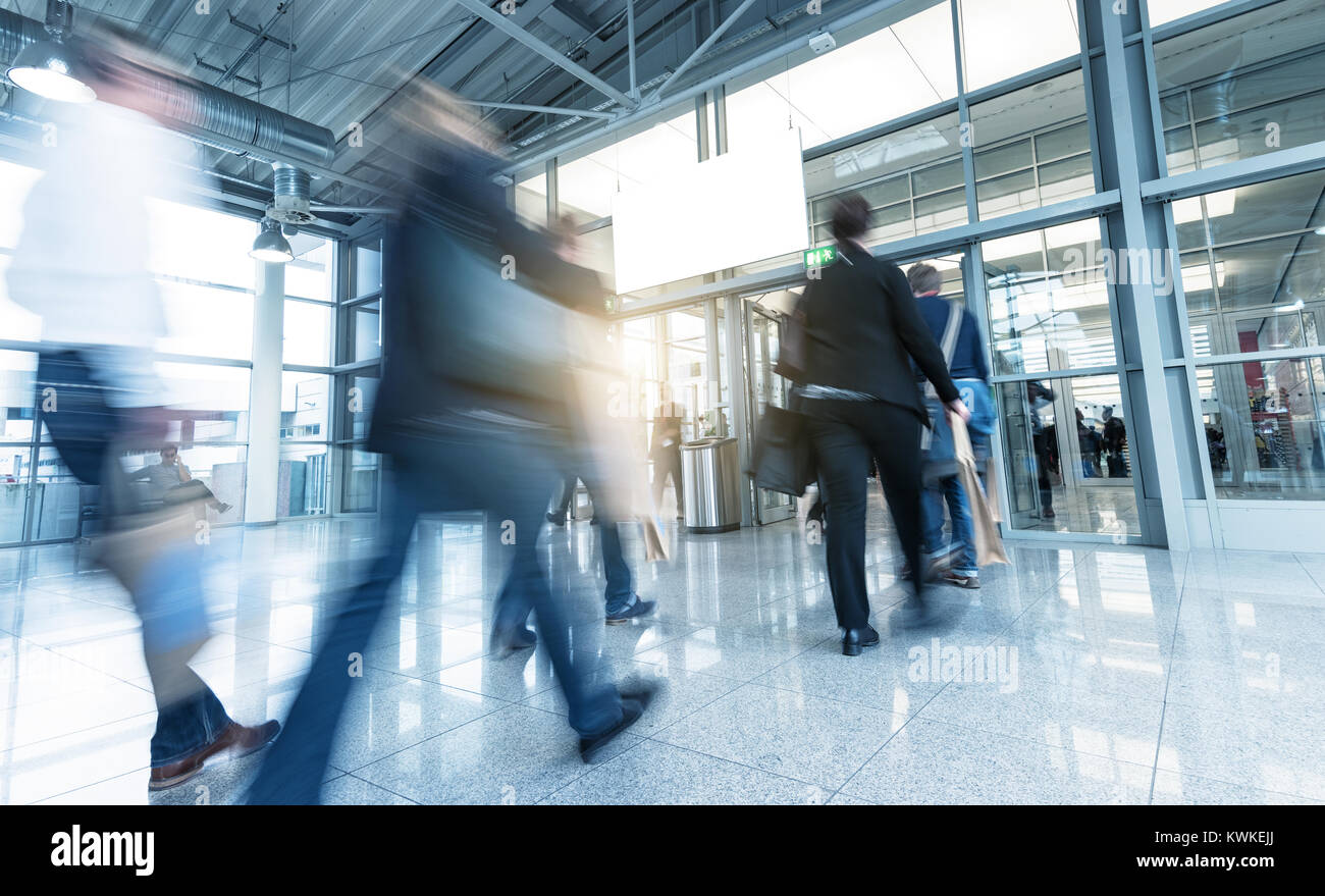 crowd of business commuters walking in a entrance at a trade show ...