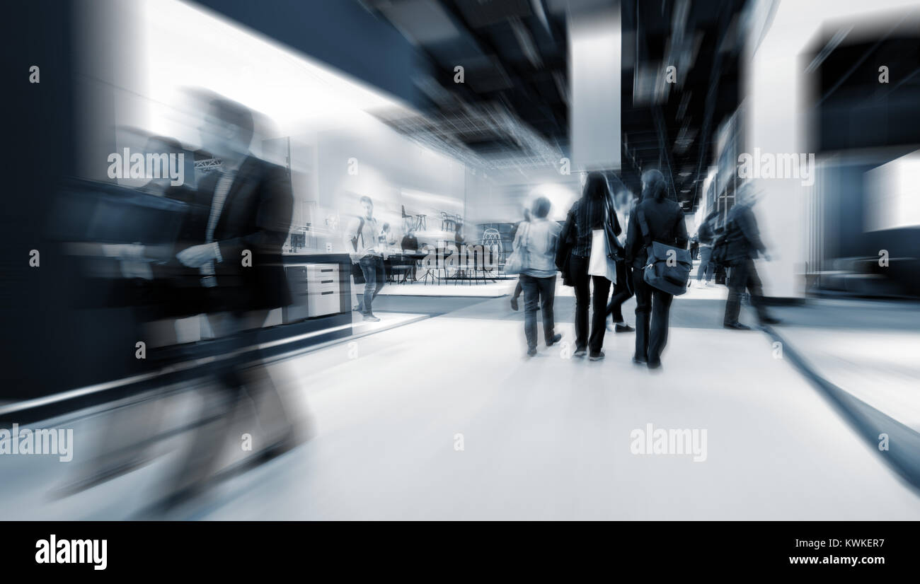 blurred business commuters walking between at trade show booths ...