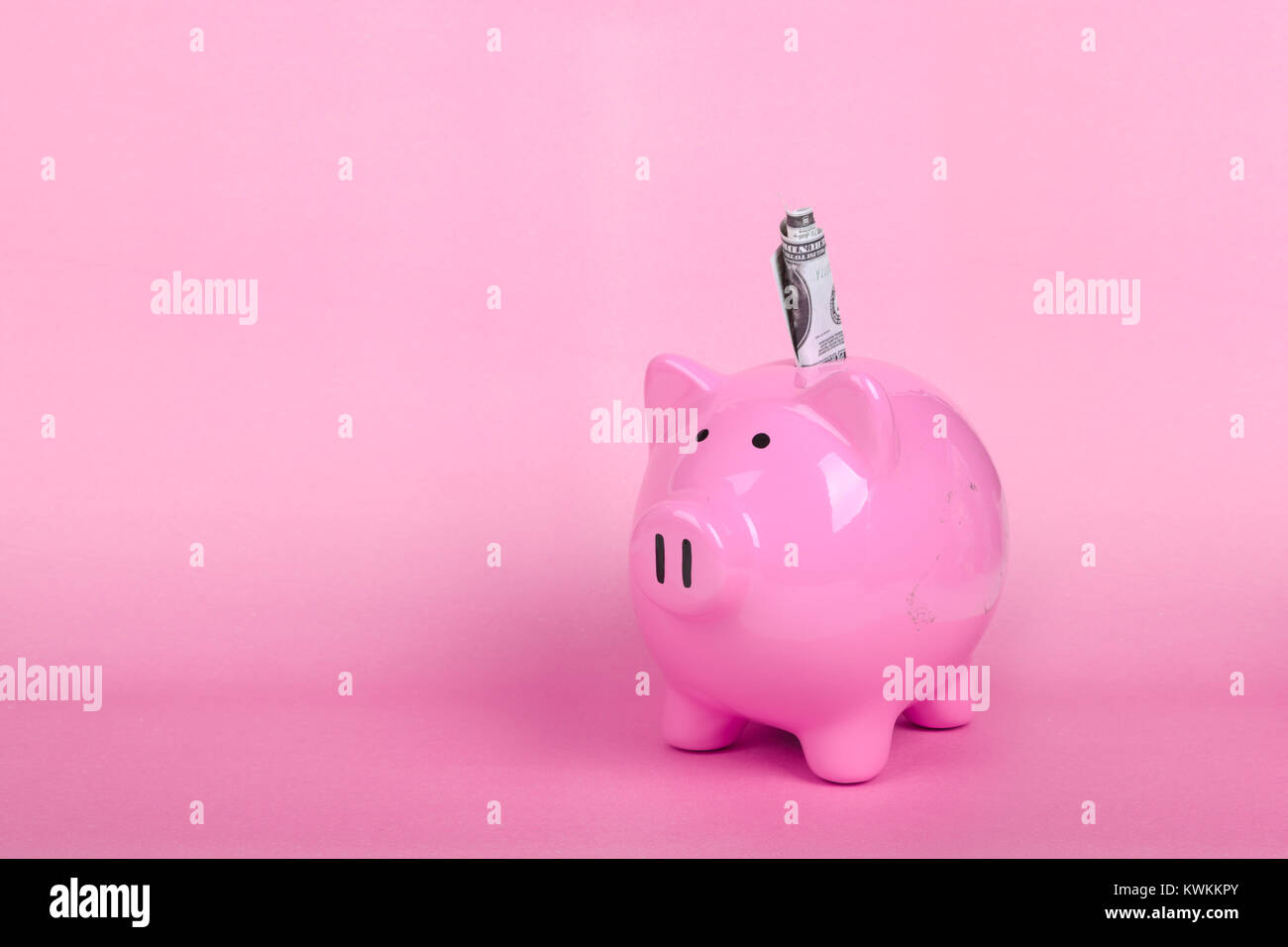 Piggy bank on soft pink background with USD dollar money banknotes ...