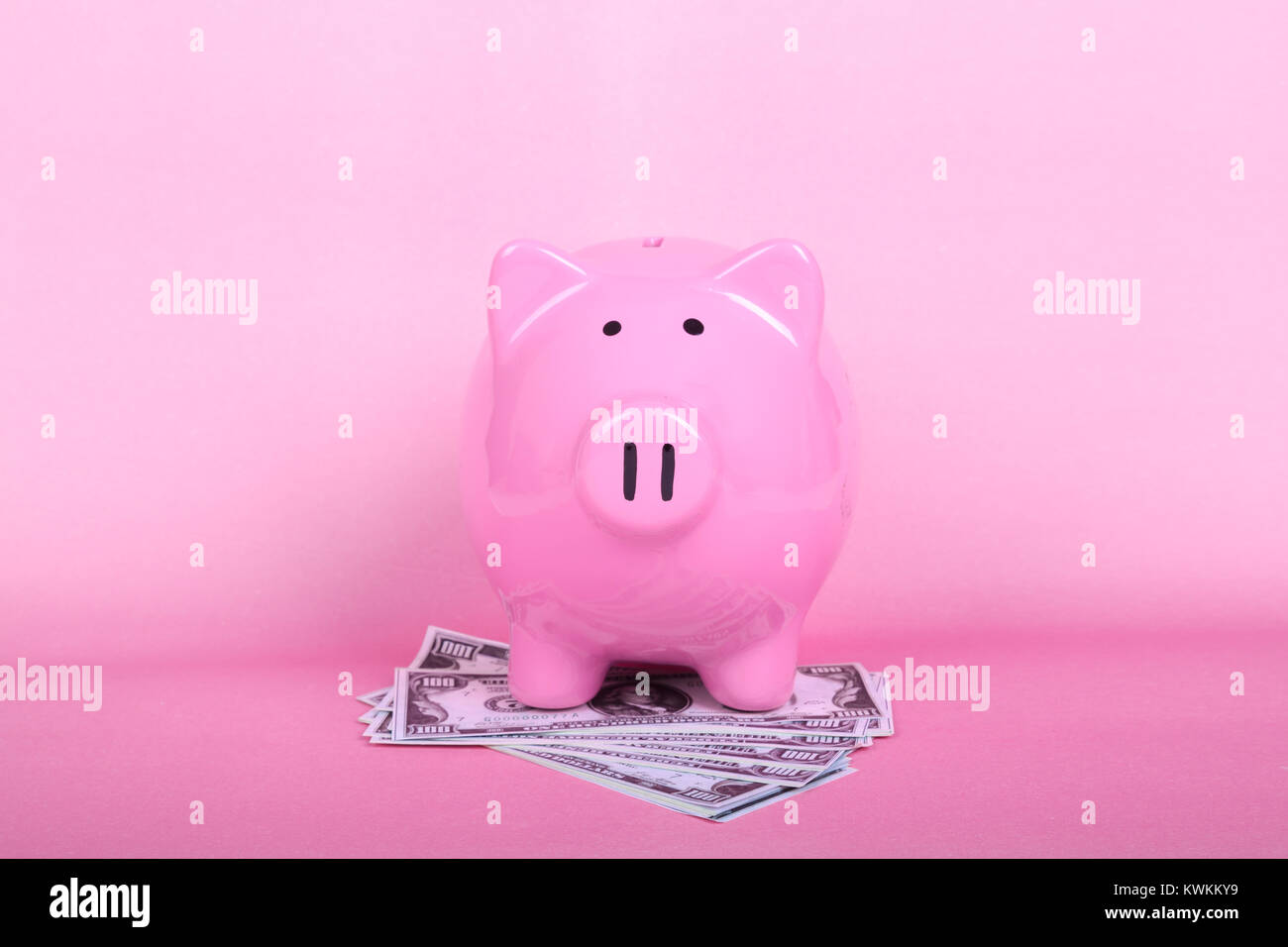 Piggy bank on soft pink background with USD dollar money banknotes ...