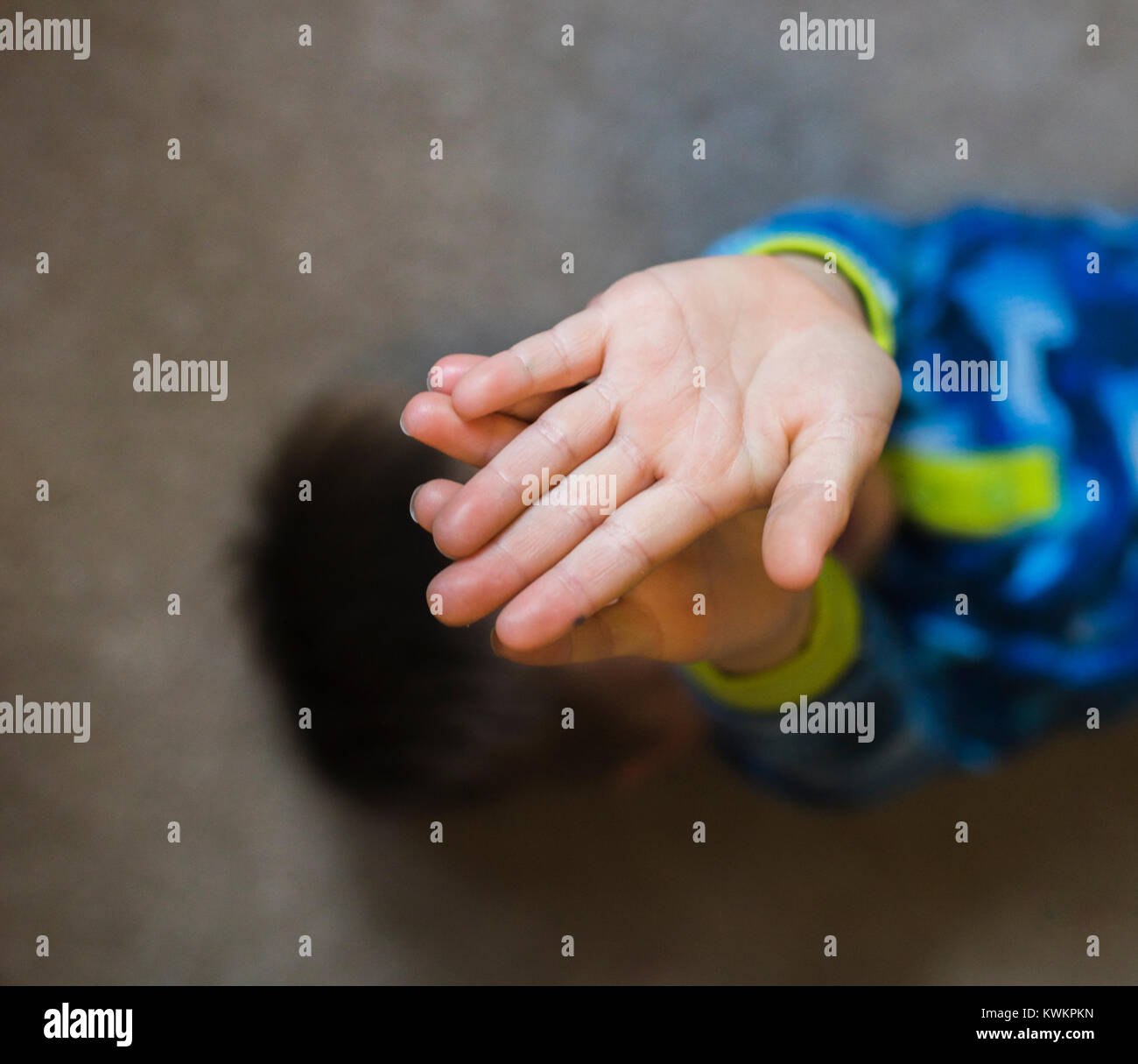 Overhead view of boy covering face while lying on floor at home Stock ...