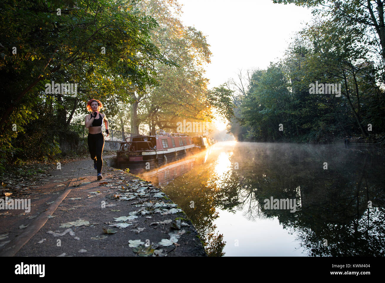 Full length of woman jogging by lake at park Stock Photo - Alamy