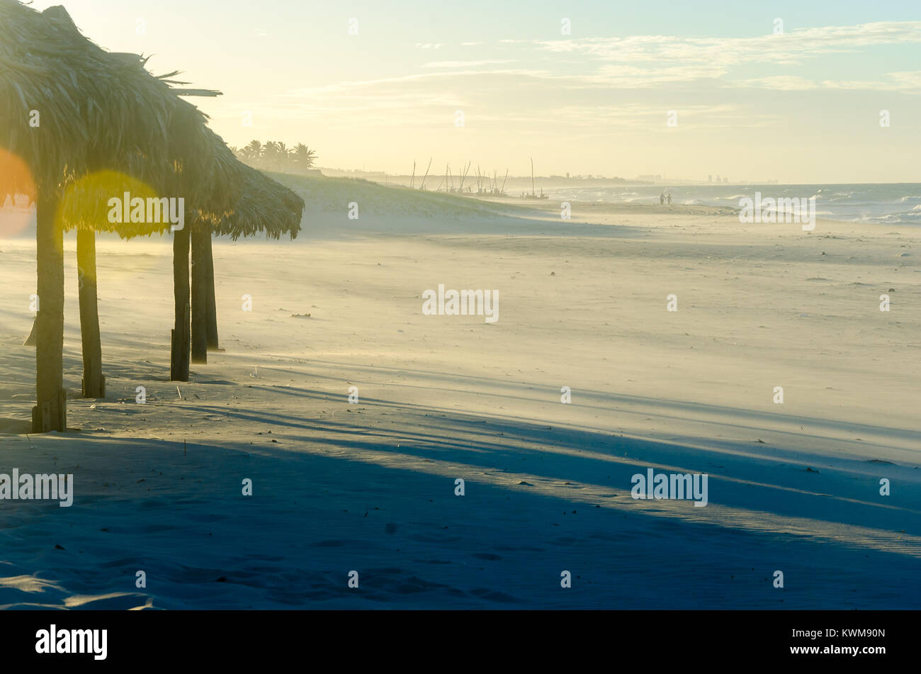 Overexposed Beach evening view with many sun umbrellas at the sunset ...