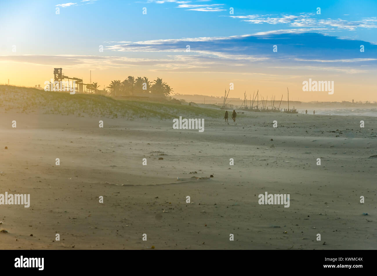 Couple on the beach at the sunset looking around Stock Photo - Alamy
