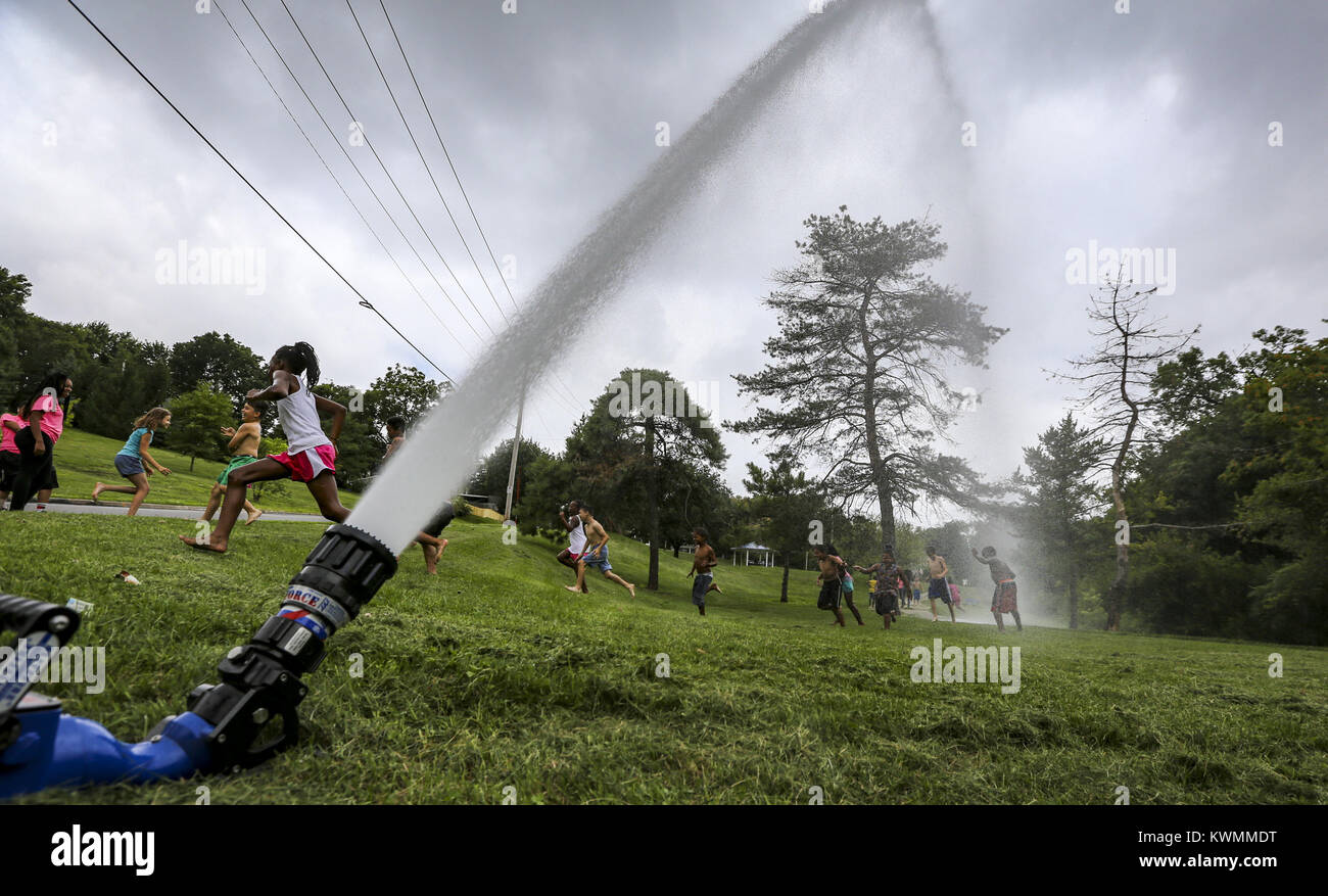 Kids run through fire hydrant water hi-res stock photography and images ...
