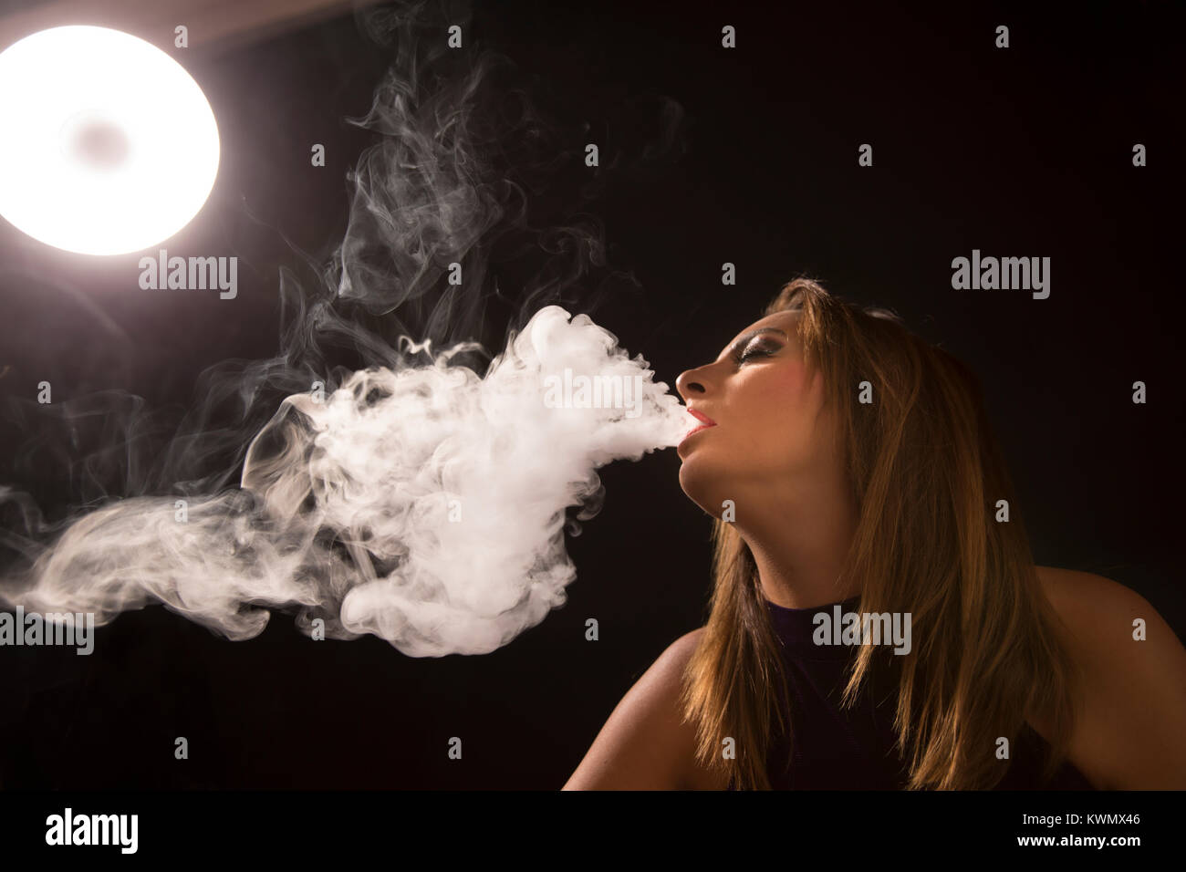 Young woman vaping. Studio shot. Black background Stock Photo - Alamy