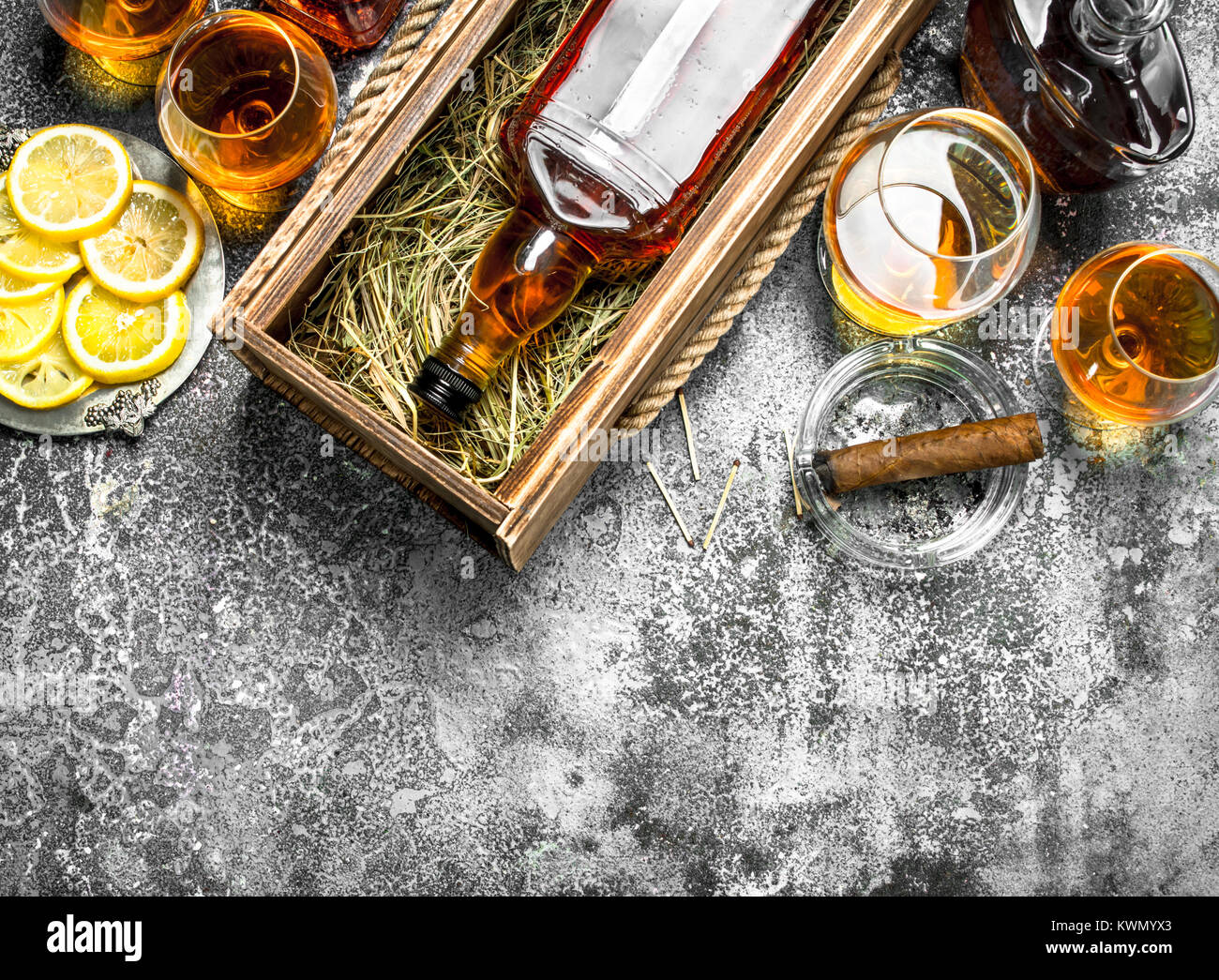 Cognac background. A bottle of cognac with lemon wedges and a cigar. On ...