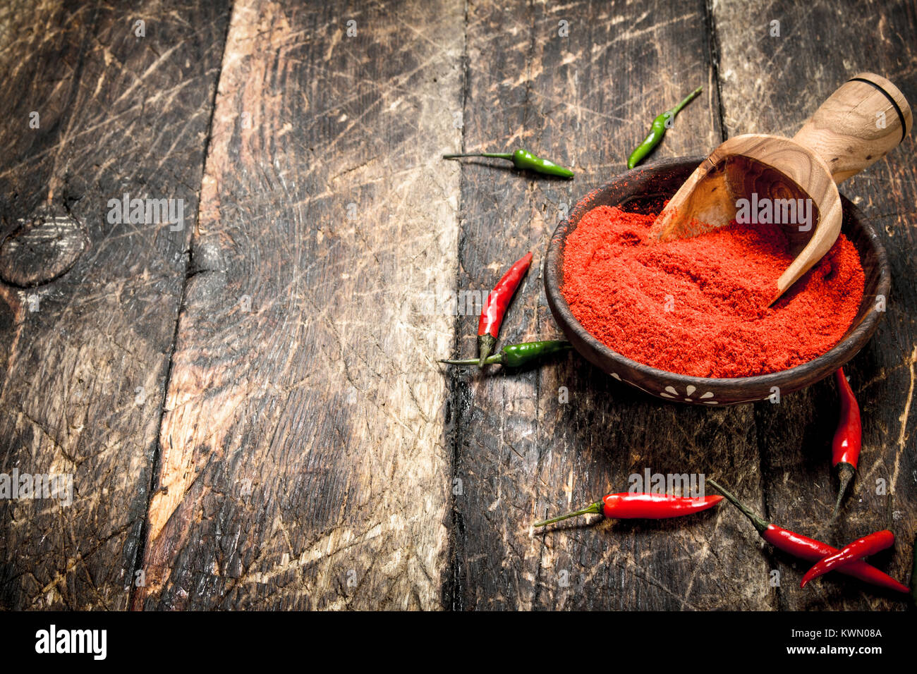 Ground hot pepper in a bowl with a scoop. On a wooden background Stock ...