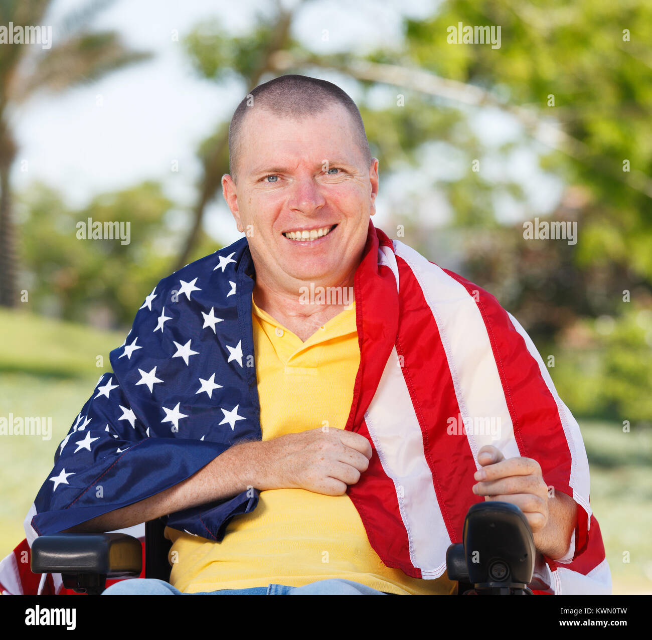 Disabled man sitting in wheelchair with flag of USA on the sholders ...