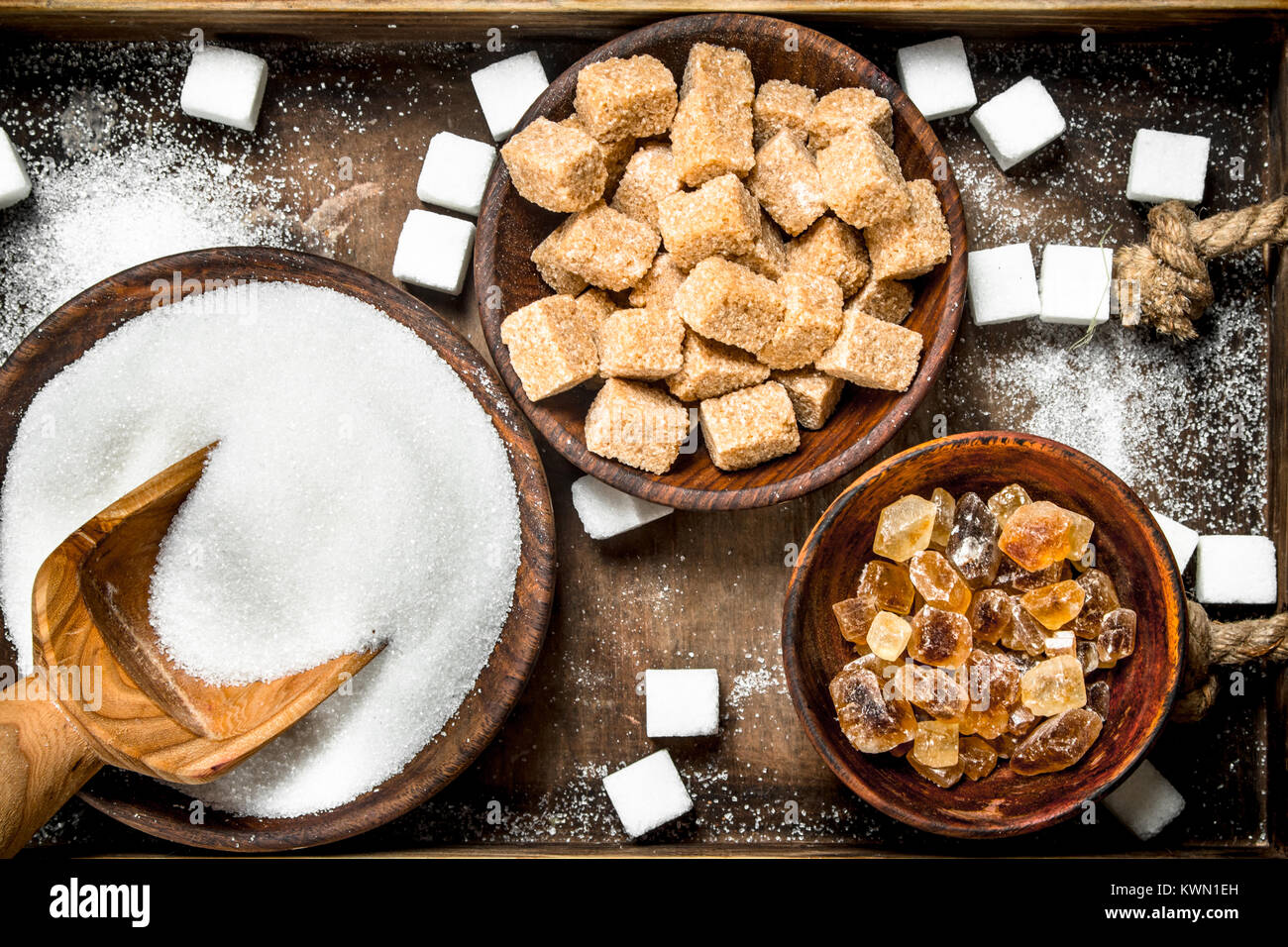 Different kinds of sugar in bowls on a tray. On a rustic background ...