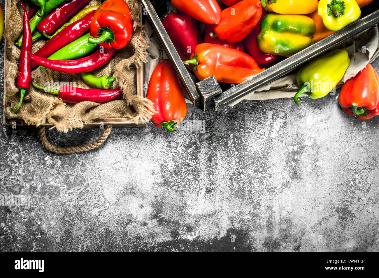 Multicolored peppers in a box and a tray. On a rustic background Stock ...