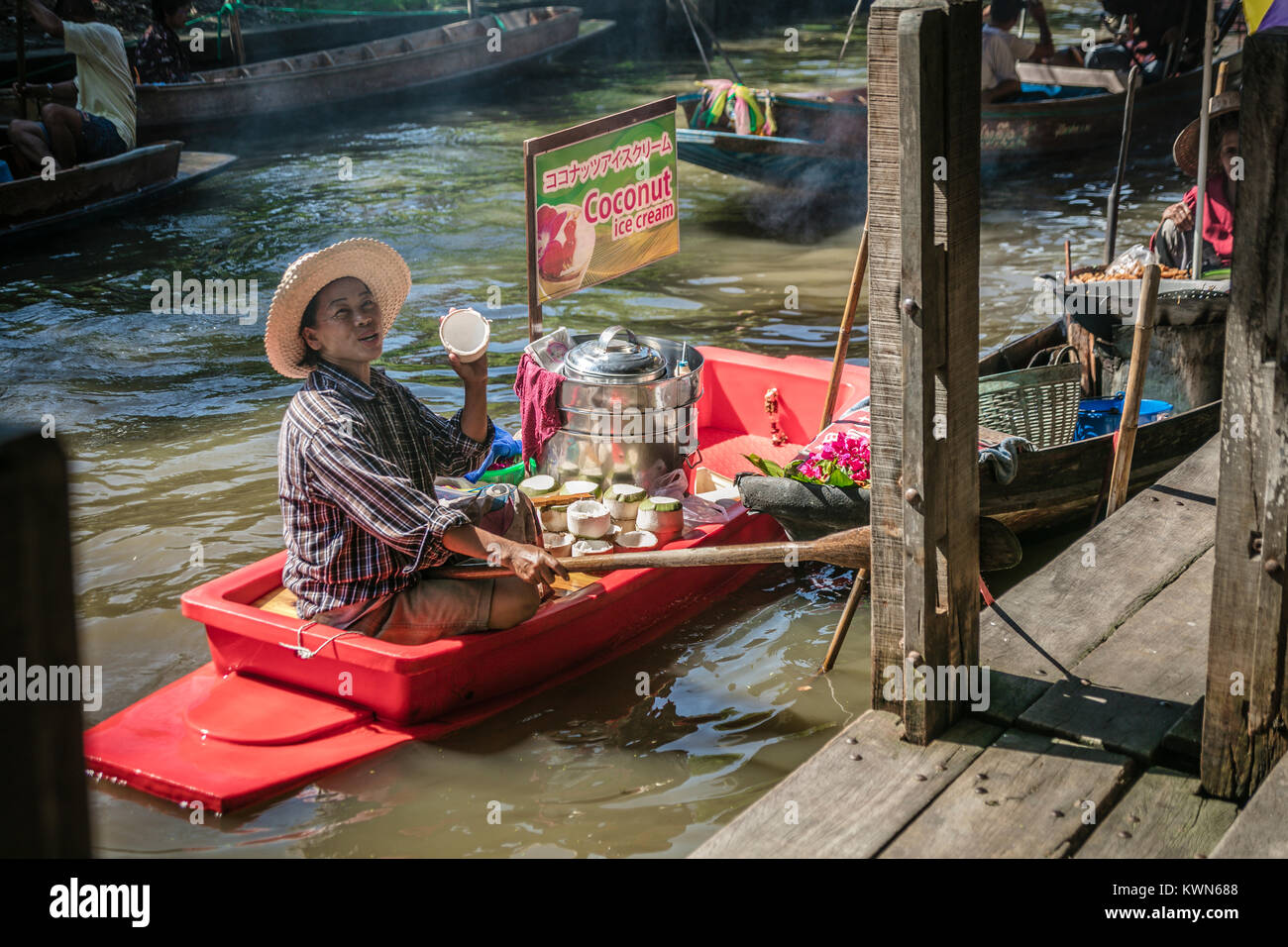 Thai trader selling coconut ice cream from boat on canal, Damnoen Saduk ...