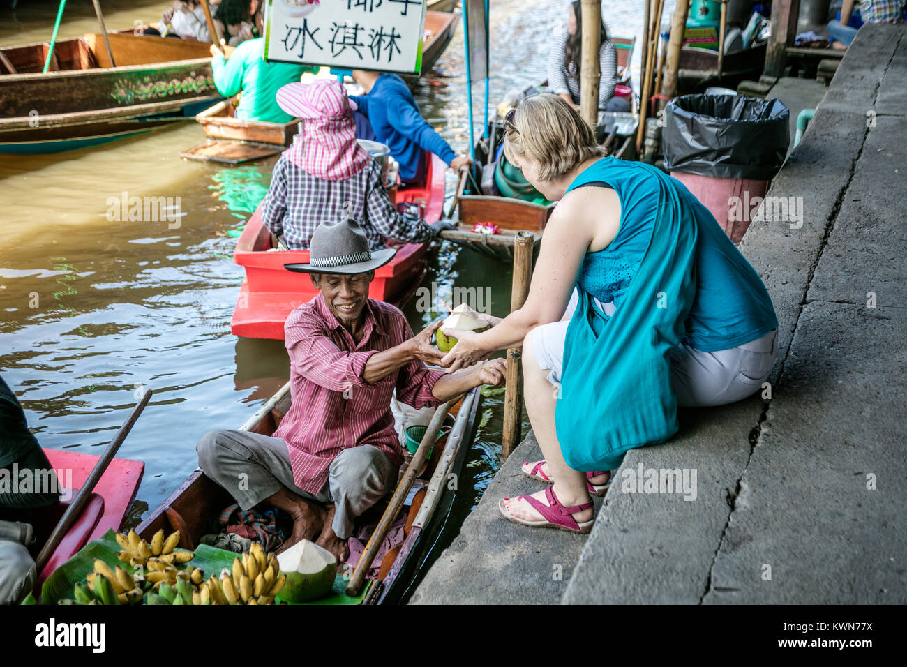 Thai trader in boat selling fresh coconut to tourist, Damnoen Saduk ...