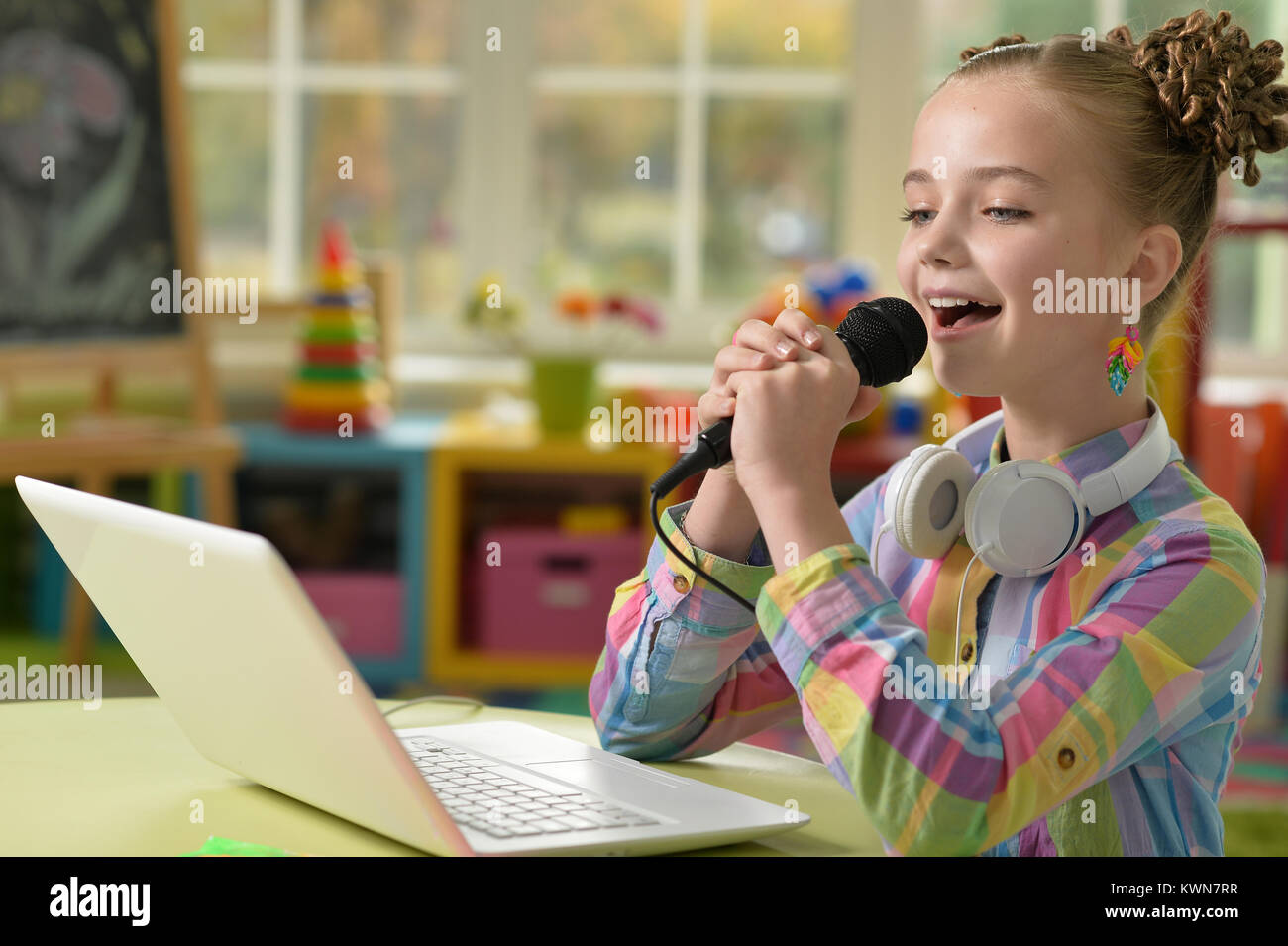 Adorable little girl using modern laptop and singing karaoke Stock ...
