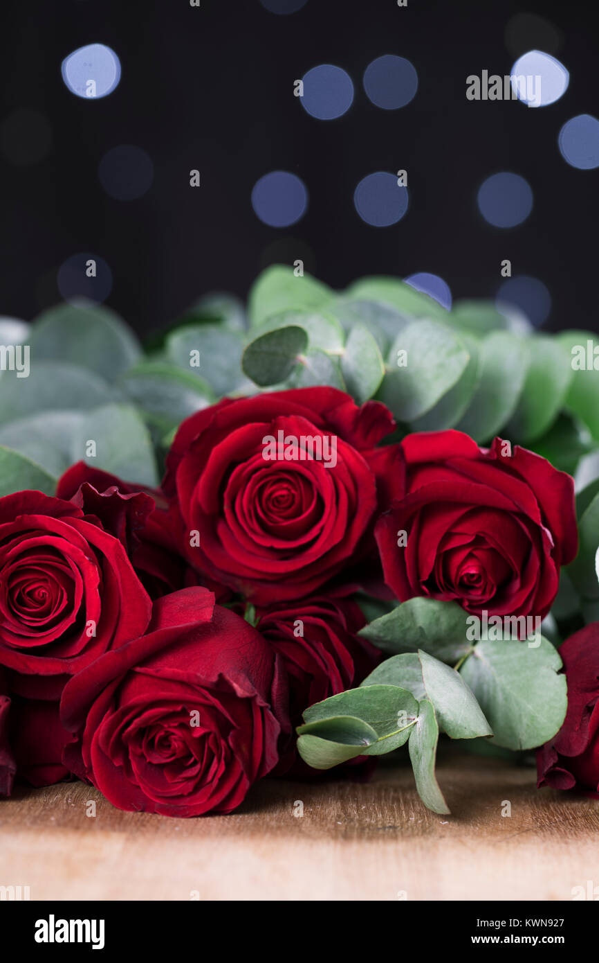 Vibrant red roses with lights in the background, vertical orientation ...