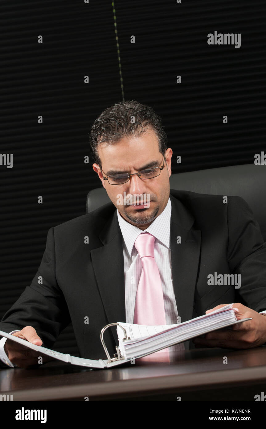 Middle Eastern business man looking at paperwork folder at his desk ...