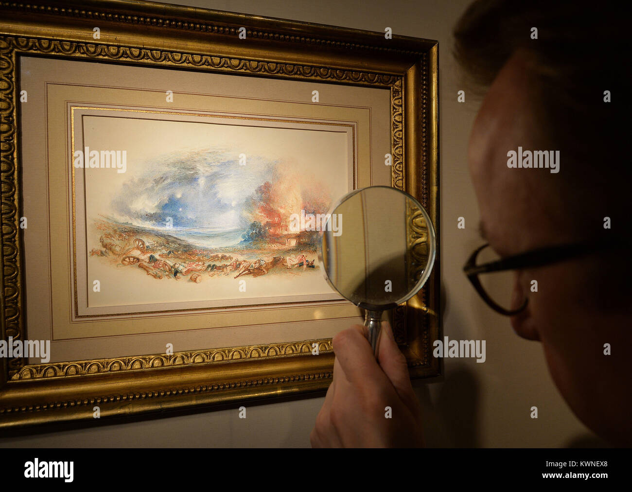 Exhibitor Simon Shore studies a small painting of the battle of ...