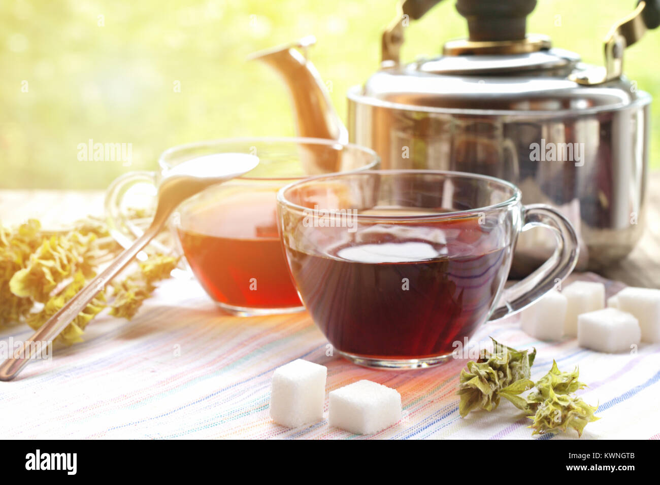Herbal tea in sunny summer day. Transparent glass cups and a metal ...