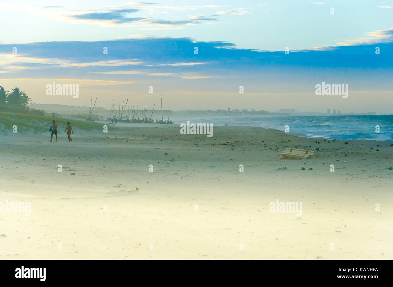 Couple on the beach at the sunset looking around Stock Photo - Alamy
