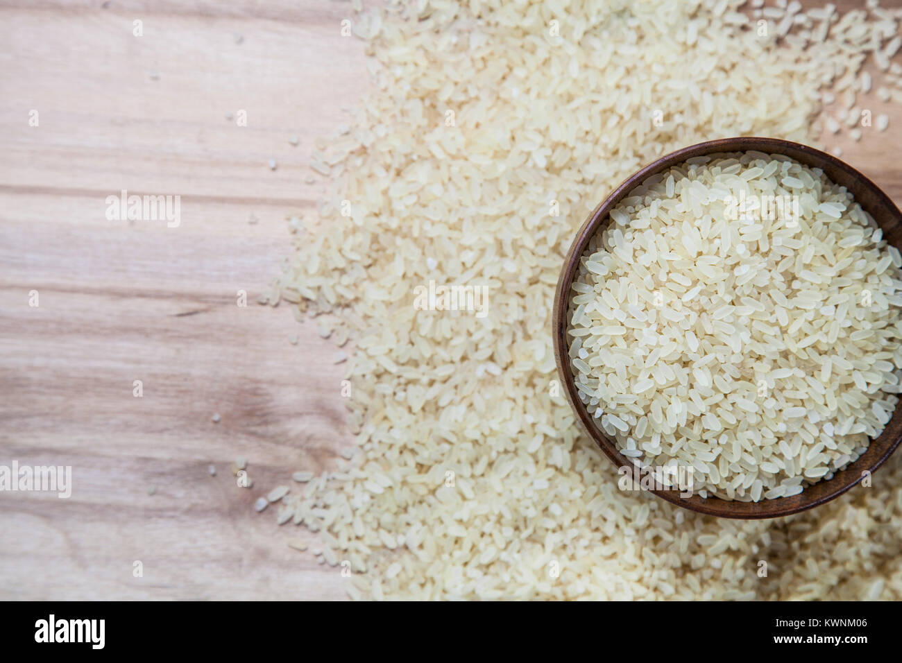 Raw long-grain steamed rice in a bowl on a wooden background ...