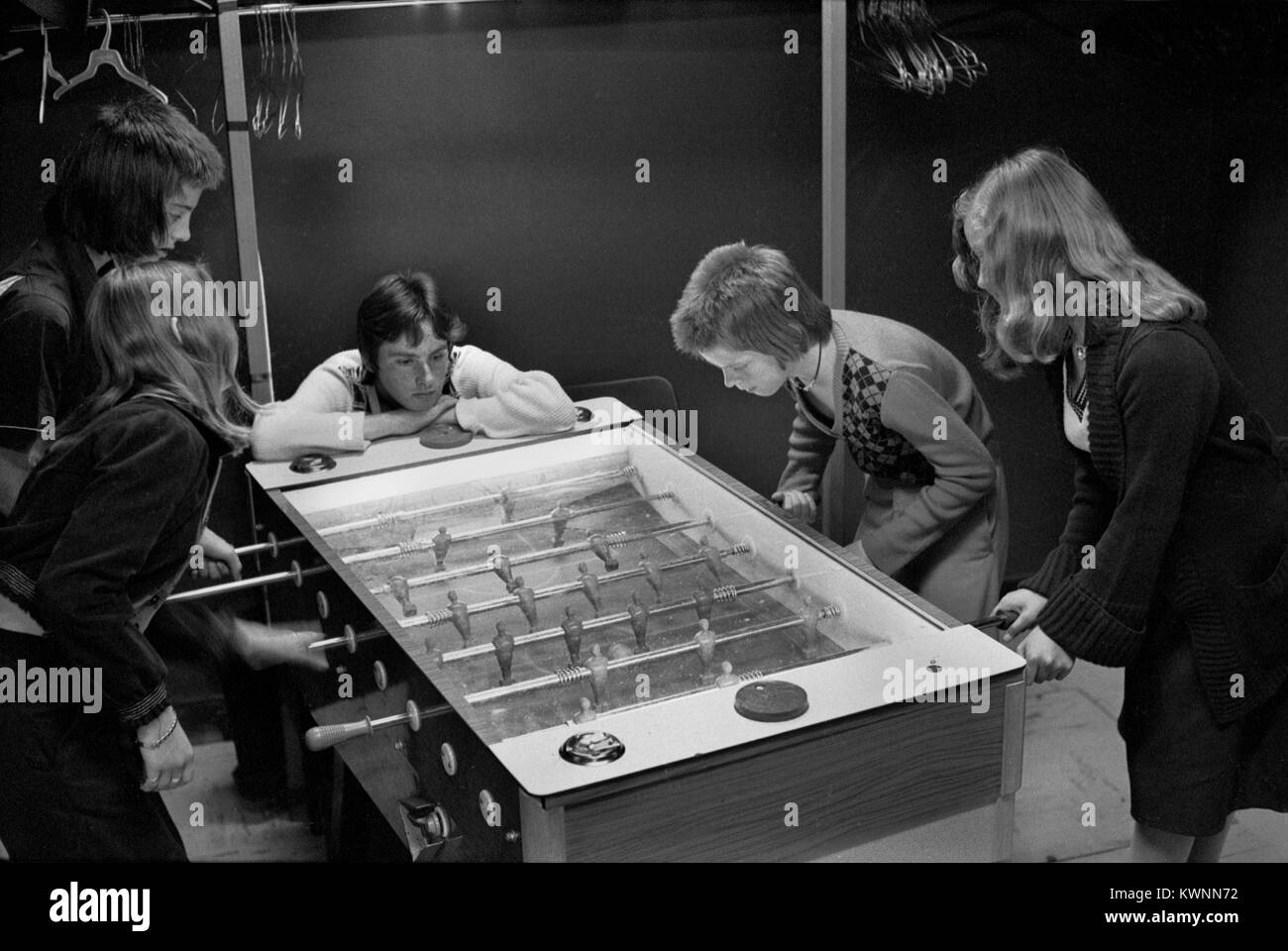 Teenager girls and boys playing mini foot, a flipper football machine ...