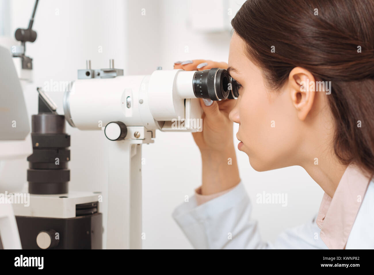 side view of professional optometrist working with slit lamp in clinic ...