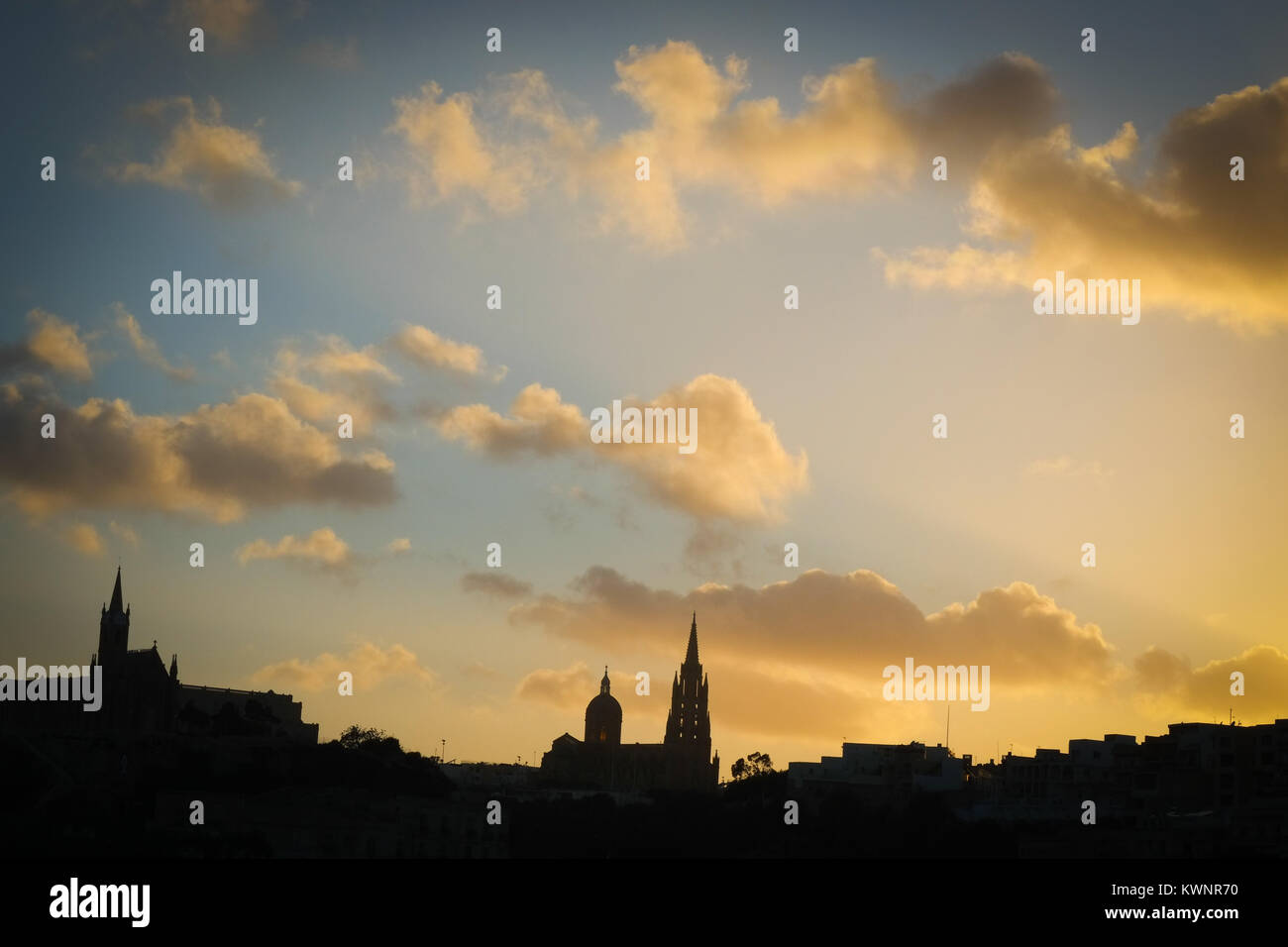 Mgarr, Gozo skyline silhouette from the sea with churches, clouds and ...